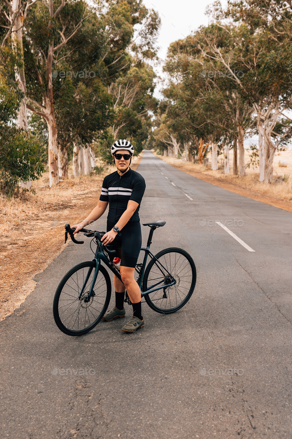 Professional woman cyclist standing with bike on a road Stock Photo by ...
