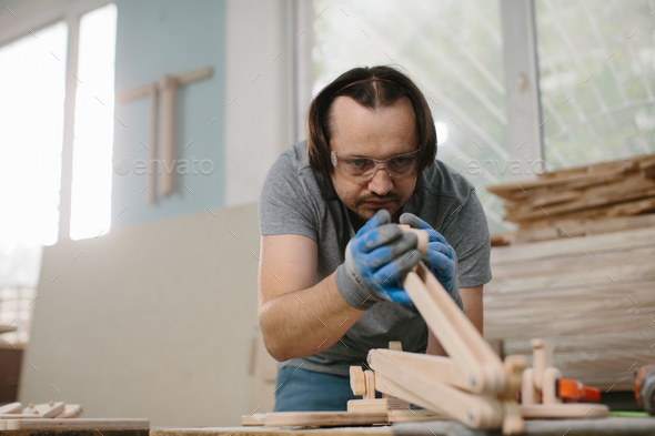 A carpenter makes wooden toys in a carpentry workshop. Making a bed ...