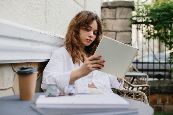 Mockup image magazine book. The girl at the coffee shop table reading ...