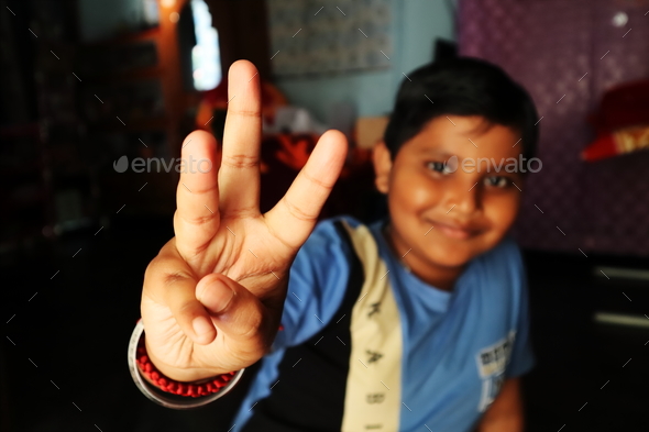 A kid showing three fingers with a smiling face in the back Stock Photo ...