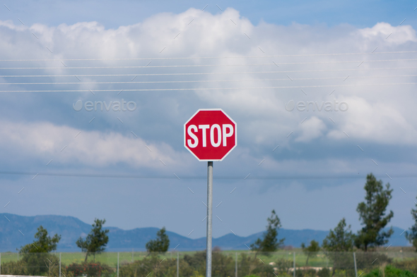 View of a stop sign in a field under the blue sky Stock Photo by wirestock
