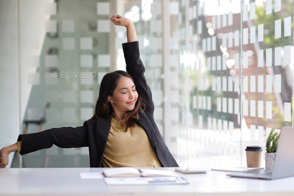 A business woman working in an office stretches to relax from work ...