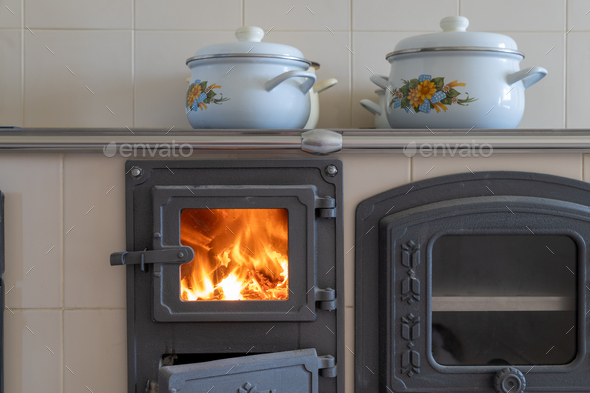 Wood burning tiled stove with fire in the kitchen. Stock Photo by jakub ...