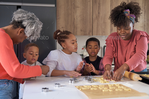 African family cutting cookie shapes in a cookie dough in the kitchen ...