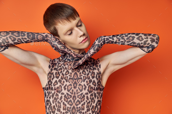 queer model in animal print outfit posing on orange backdrop, closed ...