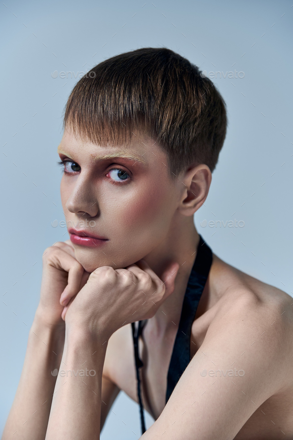 queer model looking at camera on grey backdrop, style of androgynous ...