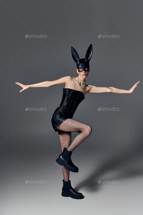 androgynous model in corset posing in bdsm bunny mask on grey, queer ...