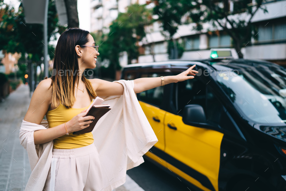Happy millennial generation Z smiling and looking for transport near city road with traffic ...
