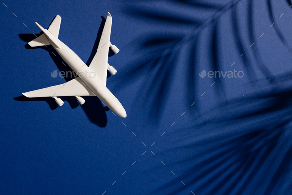 Close up of airplane model with leaves shadows on blue background with ...