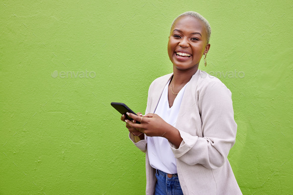 Black woman, smile and phone for portrait by a wall or green background ...