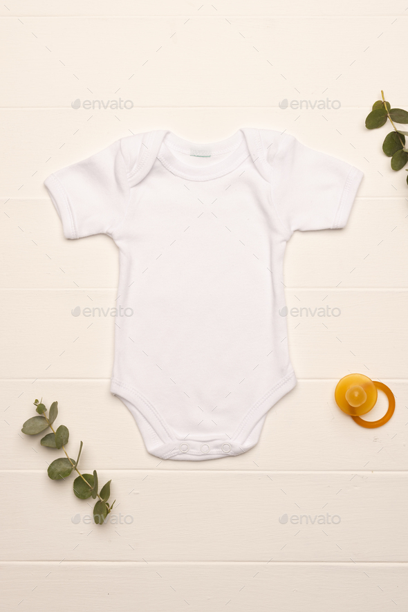 Flat lay of white baby grow and dummy with copy space on white ...