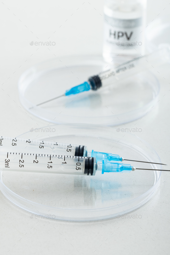Vertical composition of hpv vaccine vial and syringes on white ...