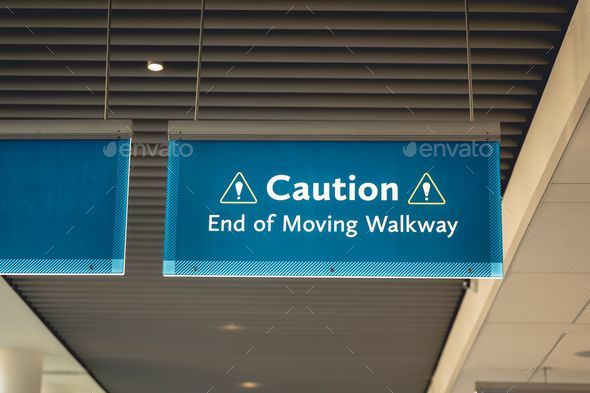 Hanging blue cation sign warning the end of a moving walkway Stock ...