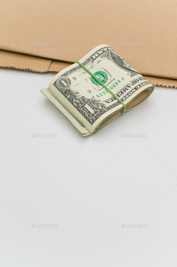isolated US dollar banknotes wad on a white and brown paper background ...