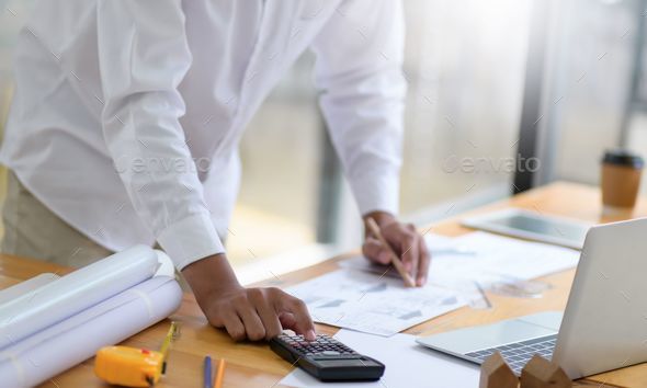 Architect using a calculator to calculate the scale of the house plan ...