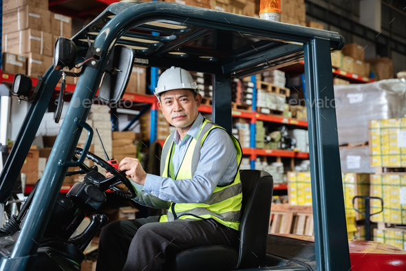 A warehouse worker forklift operator moves packages around with a ...