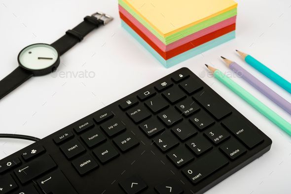 A closeup of a workspace with a computer keyboard, colorful sticky ...