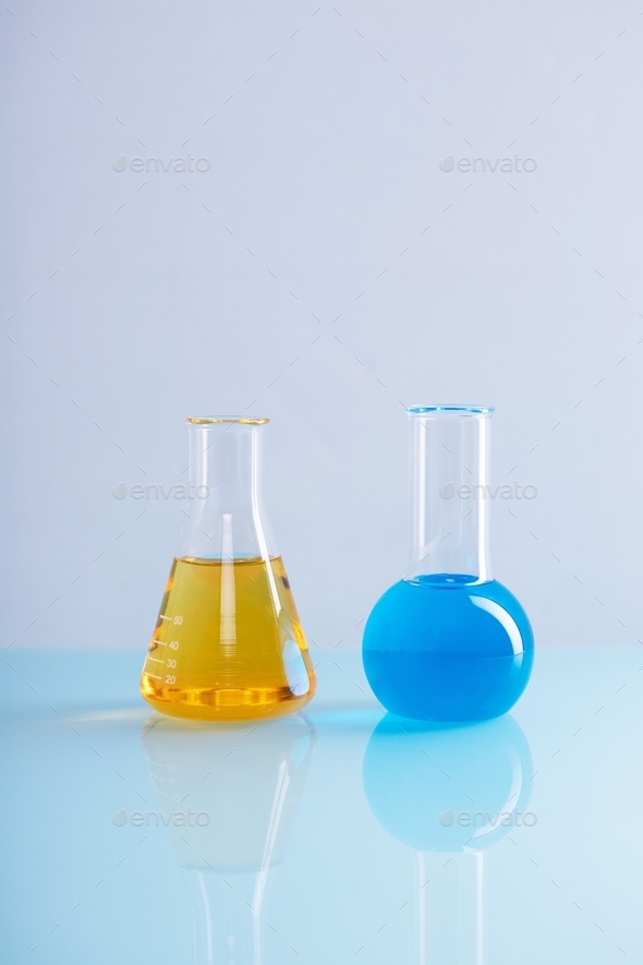 Vertical shot of Erlenmeyer flask with yellow liquid and a round flask ...