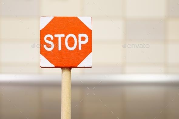 Red Stop sign in the street in front of a wall Stock Photo by wirestock