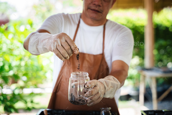 Farmer shows his hand putting the earthworm into the bottle on blur ...