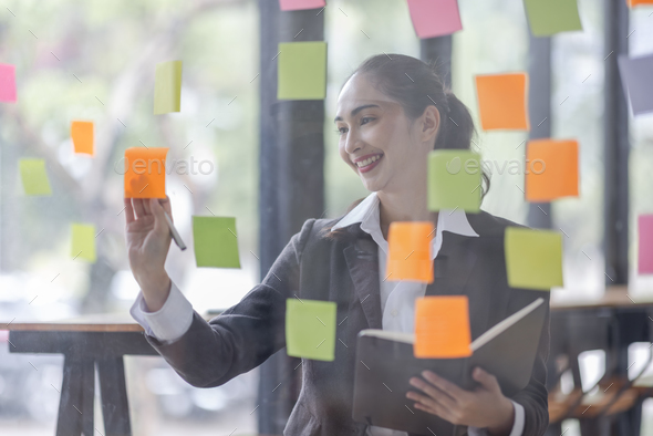 Young Serious Asian Creative team use post it notes to share idea ...