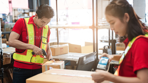 Warehouse worker checking details stock product and scanning a barcode ...
