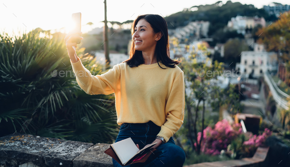 Cheerful student with smartphone technology photographing village ...