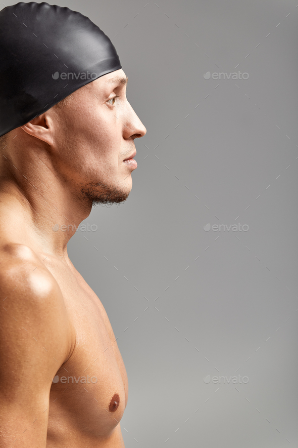 portrait of a young man swimmer wearing a rubber hat, standing against ...