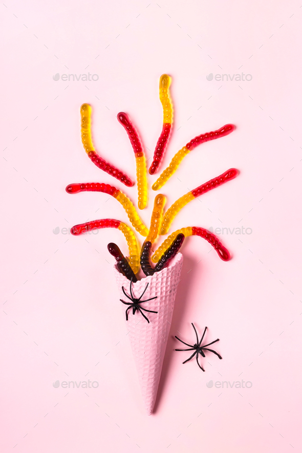 Pink ice cream cone with colorful marmalade worms and spiders. Minimal ...
