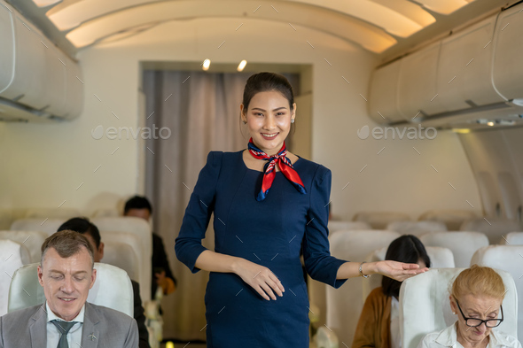 Portrait of cabin crew or air hostess in economy class cabin smiling to ...