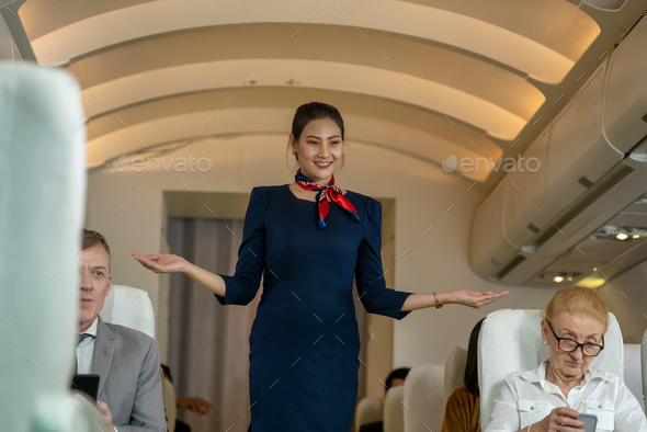 Portrait of cabin crew or air hostess in economy class cabin smiling to ...