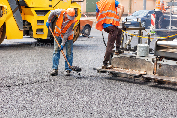 Team of road workers repairing a section of the road Stock Photo by ...