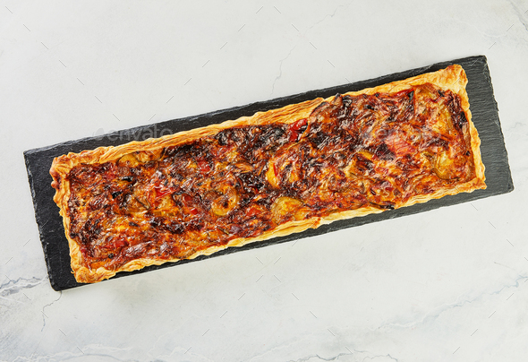Puff pastry tart with eggplant on black stone on white marble Stock ...