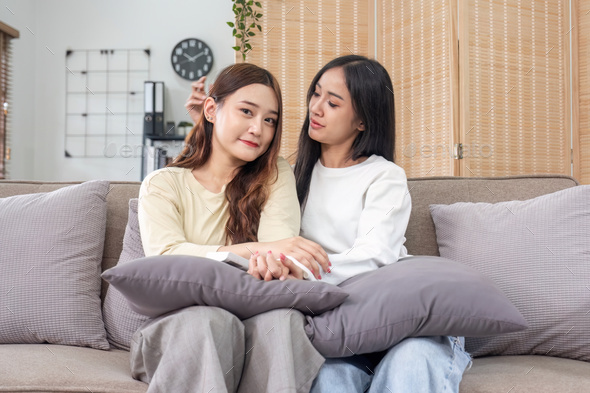 LGBT. Two young women happily lounging on the sofa in the living room. Stock Photo by wichayada69
