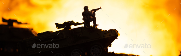 Battle scene with silhouette of toy soldier on tank with fire at ...
