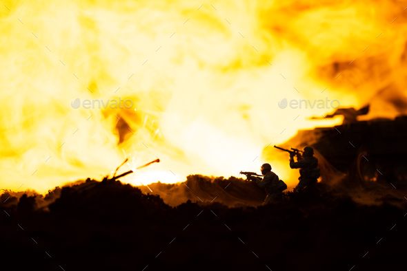 Battle scene with toy soldiers and tank on battleground with fire at ...