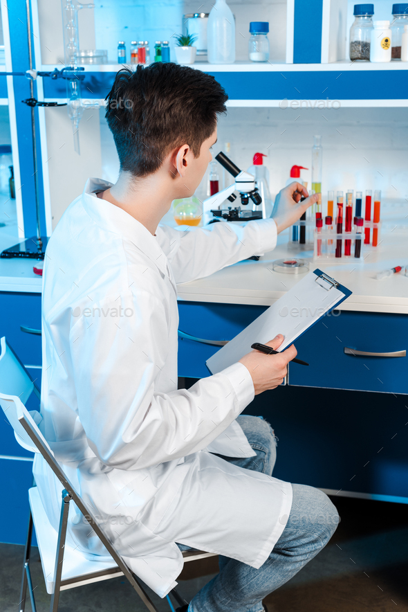 scientist in white coat holding clipboard and touching test tube Stock ...
