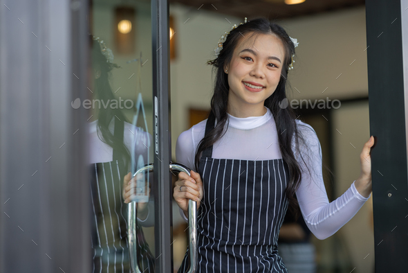 Portrait of asian smiling owner standing at her restaurant gate with ...