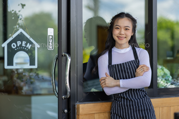 Portrait of asian smiling owner standing at her restaurant gate with ...