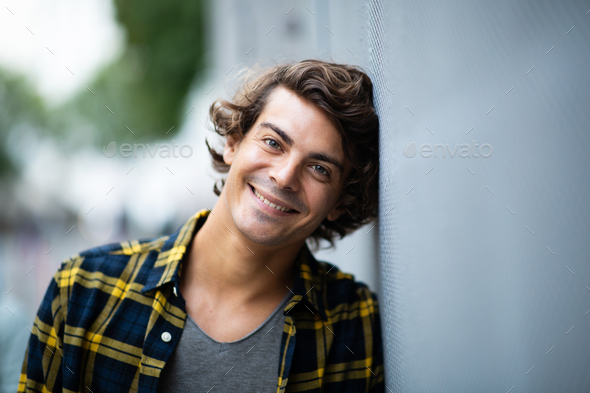 Good looking young guy leaning against gray wall and smiling Stock ...