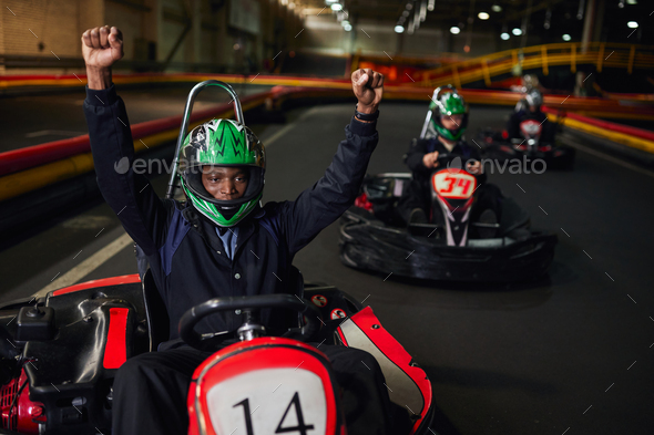 excited african american go cart racer in helmet raising hands and ...