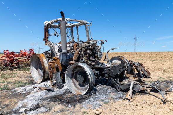 Tractor with trailer on field burned down Stock Photo by wirestock
