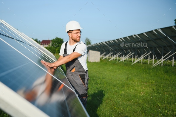 Side view of male worker installing solar modules and support ...