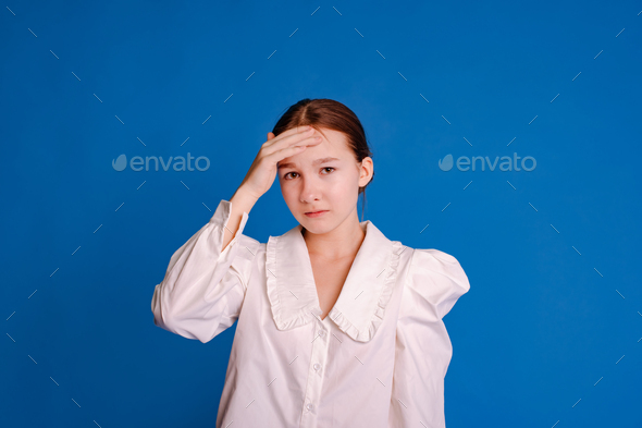 thinking student girl touching forehead with hand on light blue studio ...