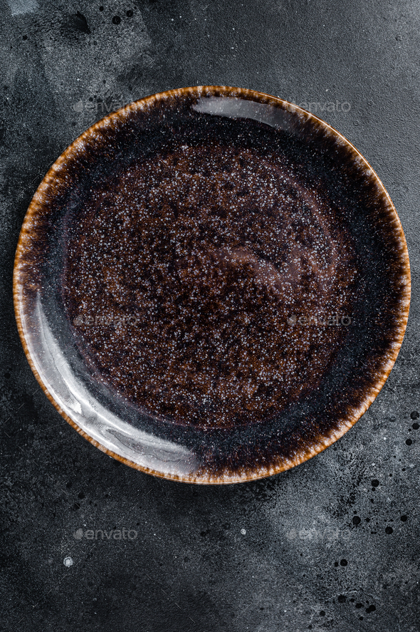 Empty black craft plate on table. Table setting. Black background. Top ...
