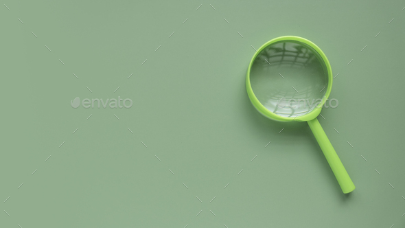 Green magnifying glass over a green background.Copy space Stock Photo ...