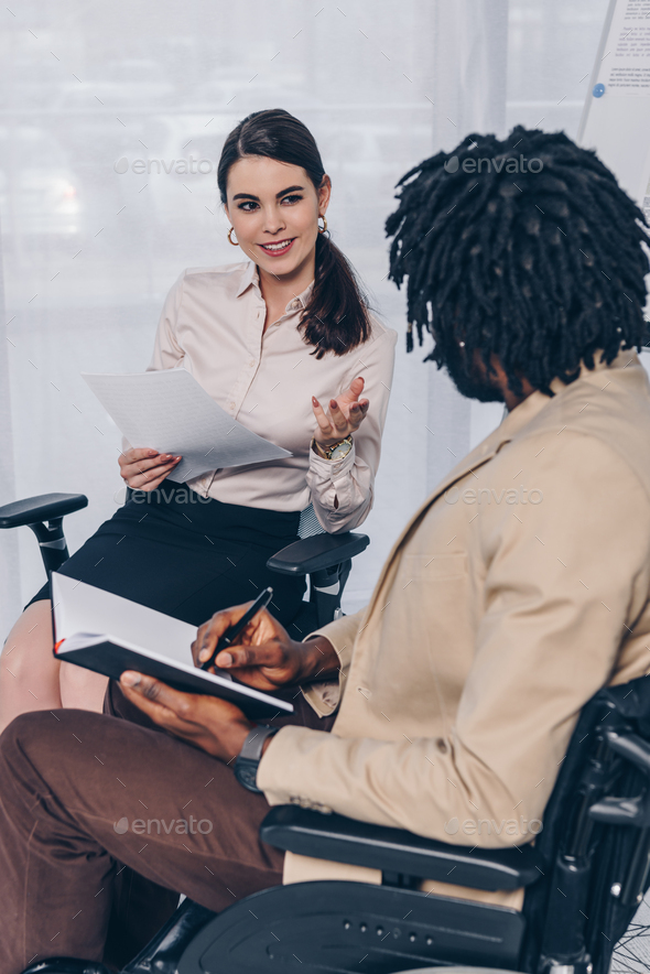 Recruiter with papers and african american disabled employee with ...