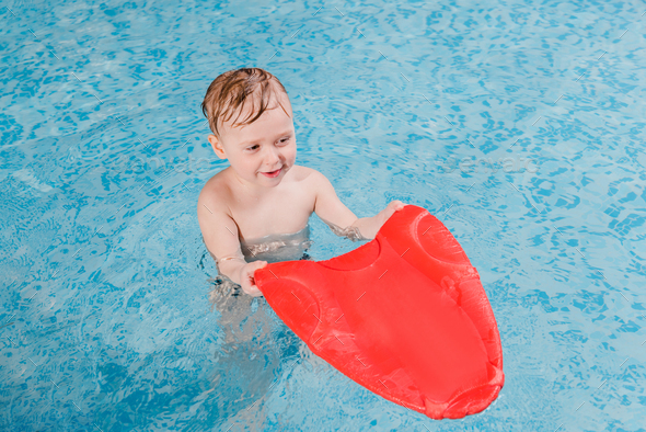 happy toddler boy swimming with flutter board in swimming pool Stock ...