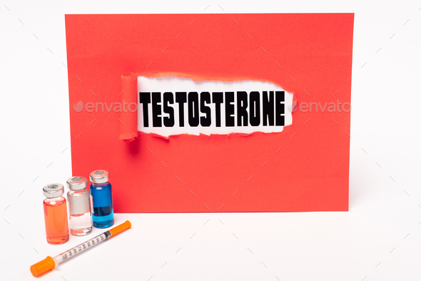 Testosterone lettering in hole of red paper, syringe and jars of ...