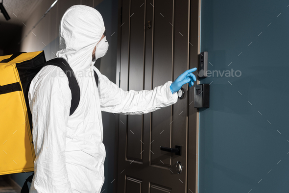 Side view of courier in hazmat suit, medical mask and latex glove ...